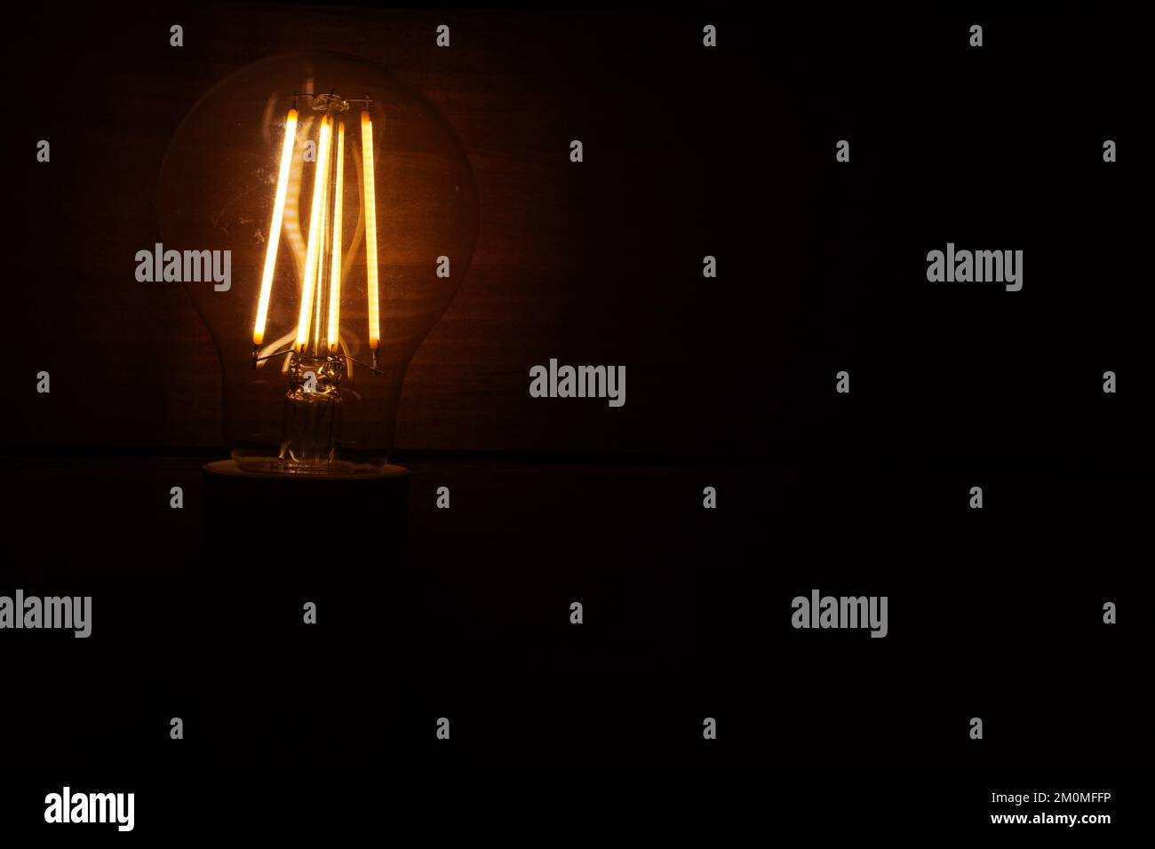 burning light bulb on wood surface and black background Stock Photo - Alamy