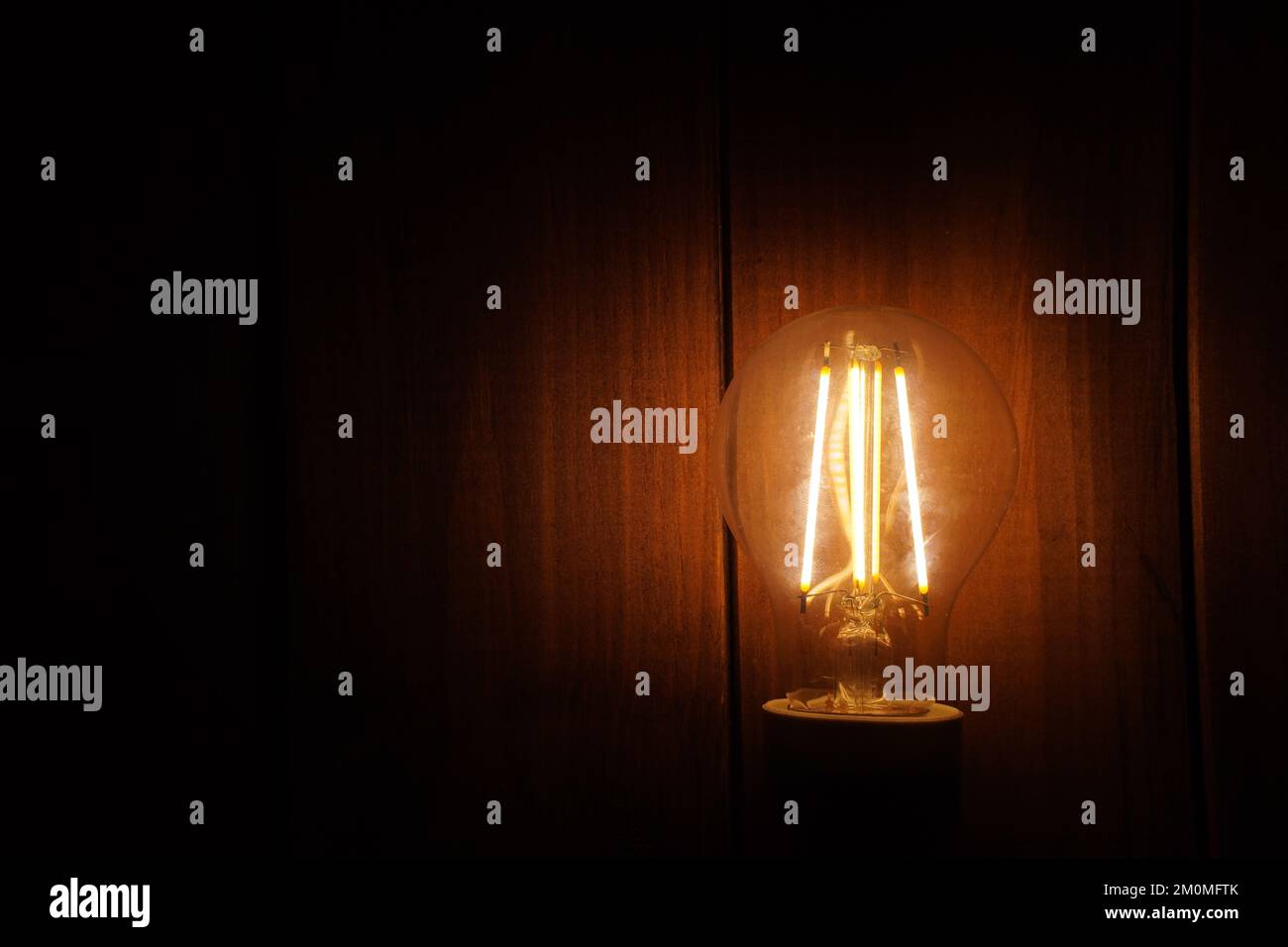 burning light bulb on wood surface and black background Stock Photo - Alamy