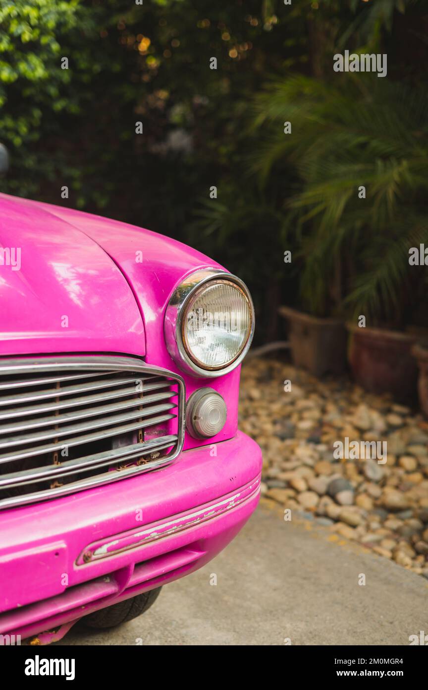 A close-up shot of the headlight of a pink retro car, vertical shot ...