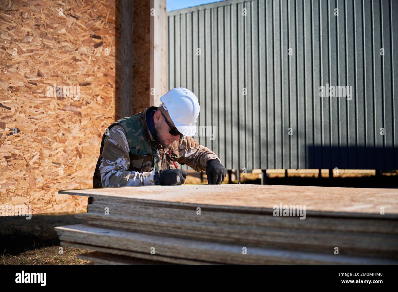 Man worker building wooden frame house on pile foundation. Carpenter ...