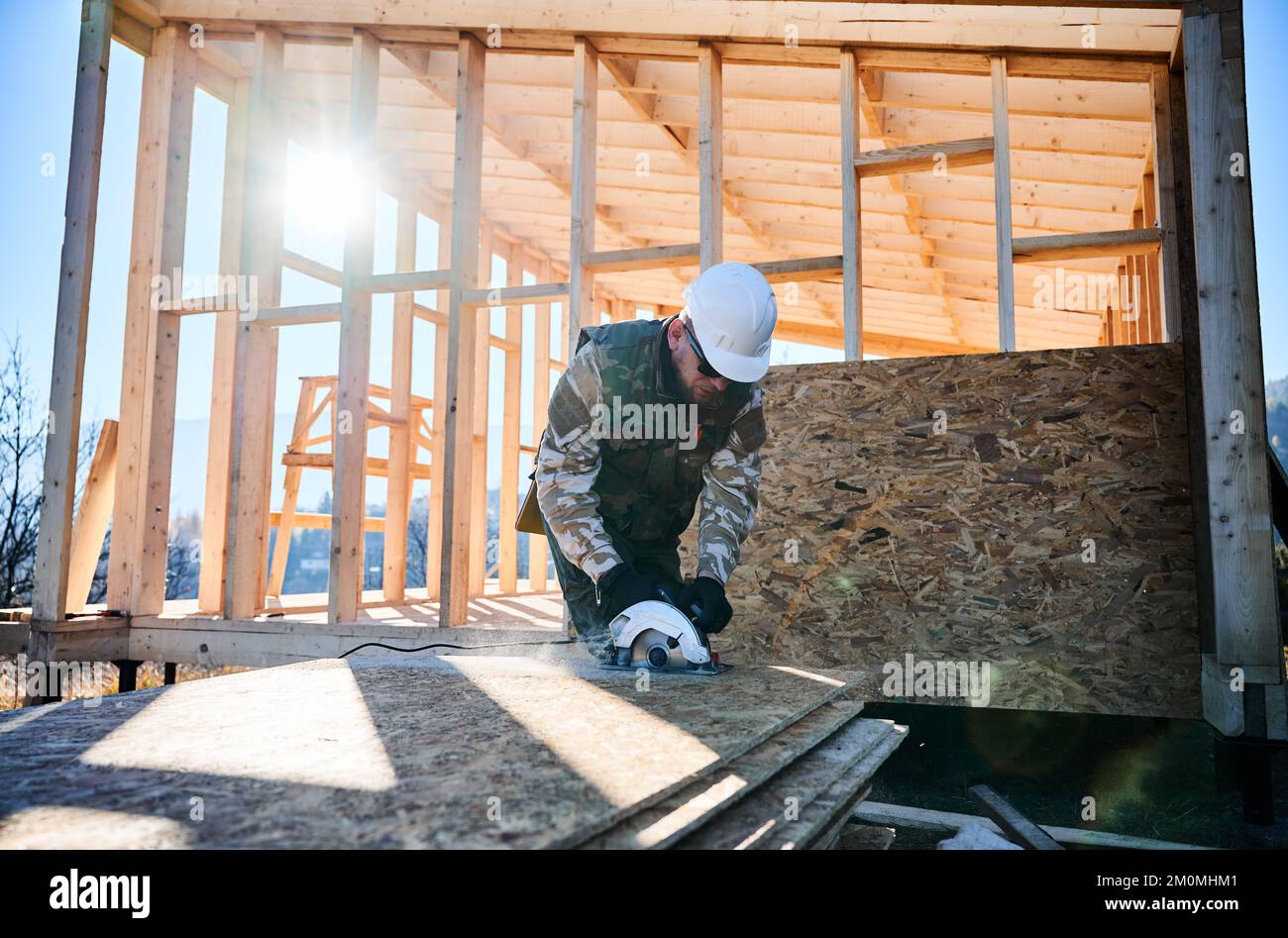 Carpenter using circular saw for cutting wooden OSB board. Man worker ...