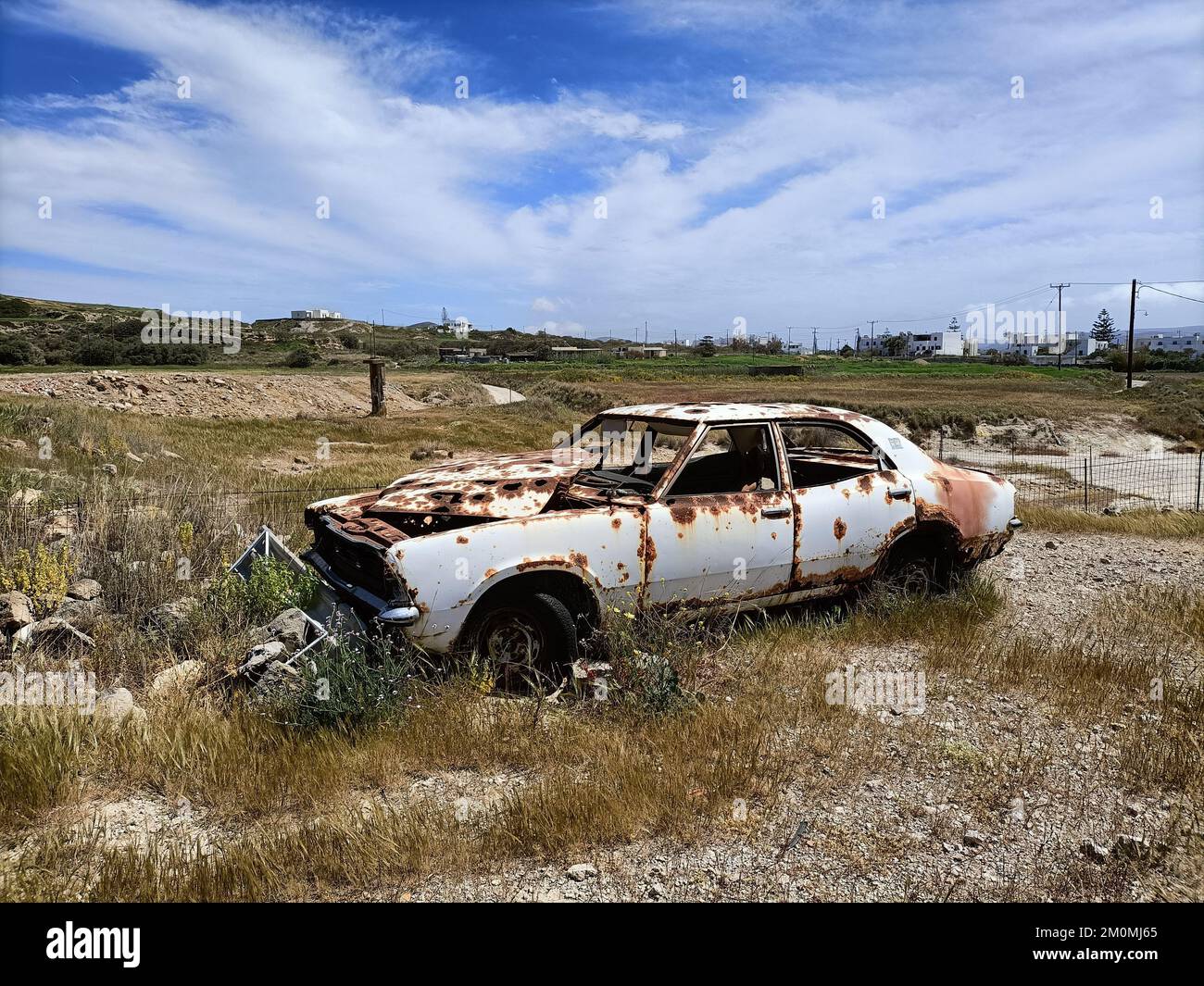 A closeup shot of an old rusty white car abandoned in the middle of a ...