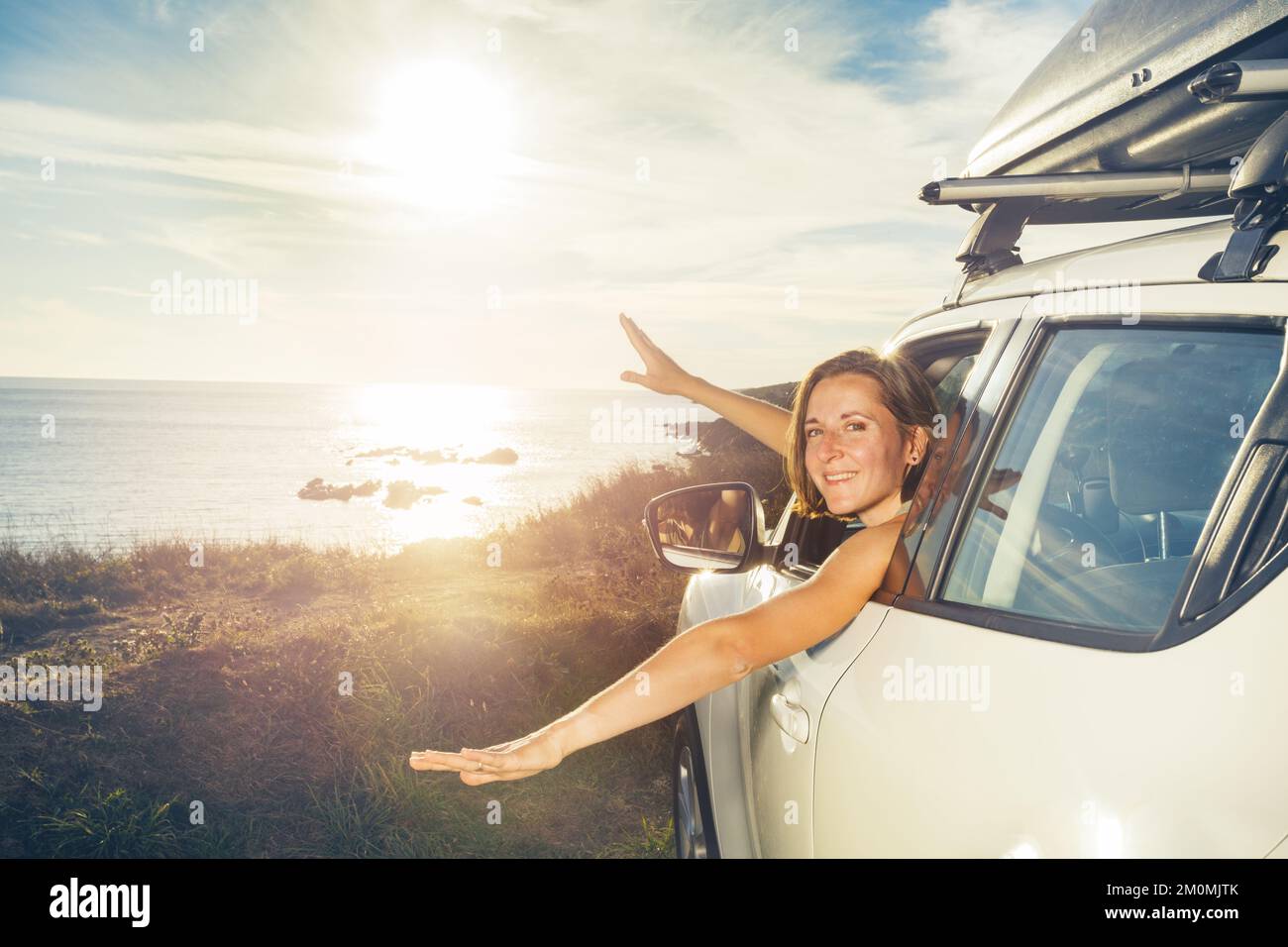 Woman smile look from car window on ocean sunset and wave hands Stock ...
