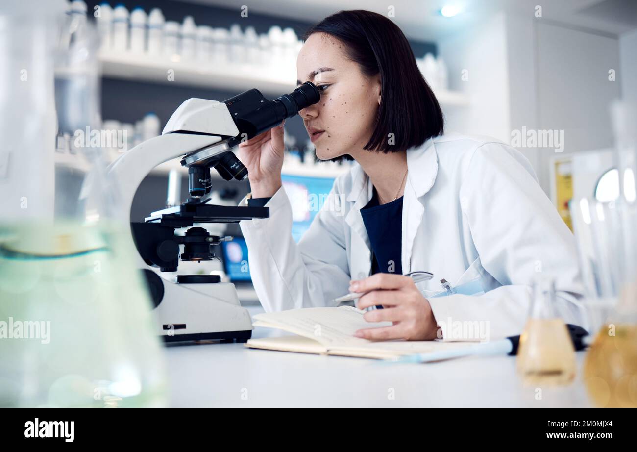 Science, microscope and writing with a doctor woman doing research in ...