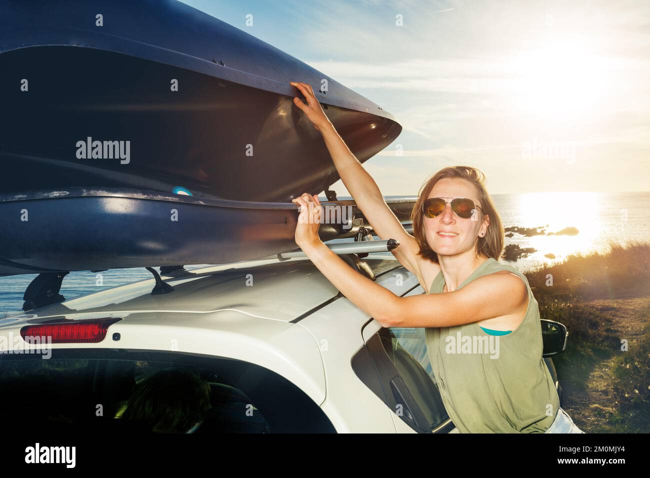 Woman in sunglasses unload car roof top baggage at sea parking Stock ...