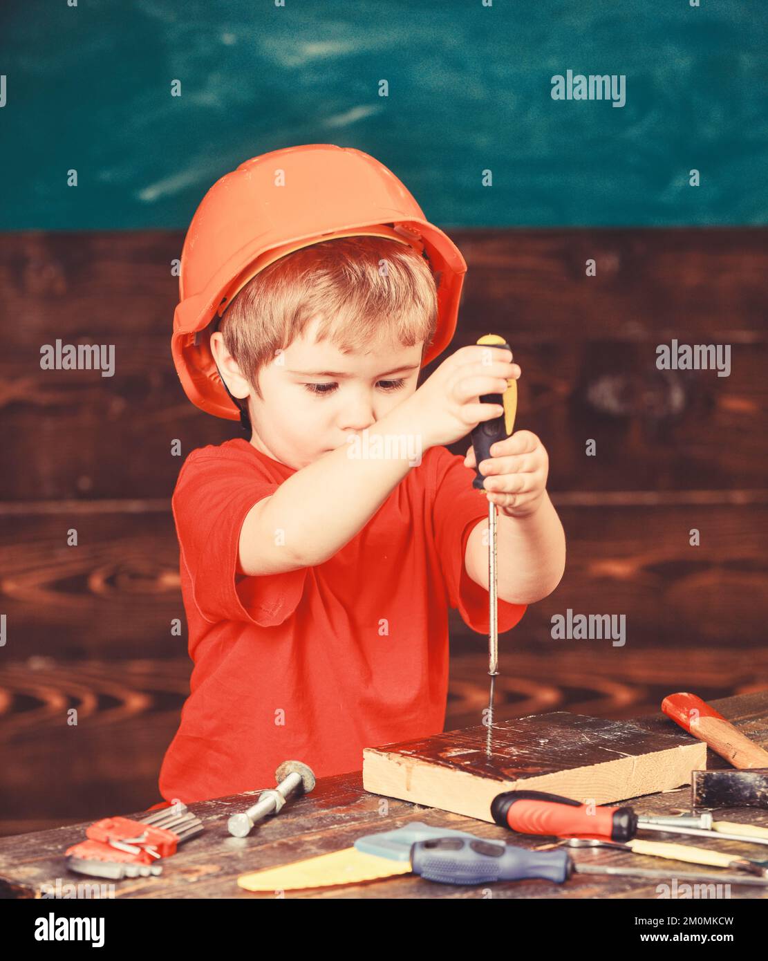 Kid boy holds screwdriver tool. Toddler on busy face plays with ...