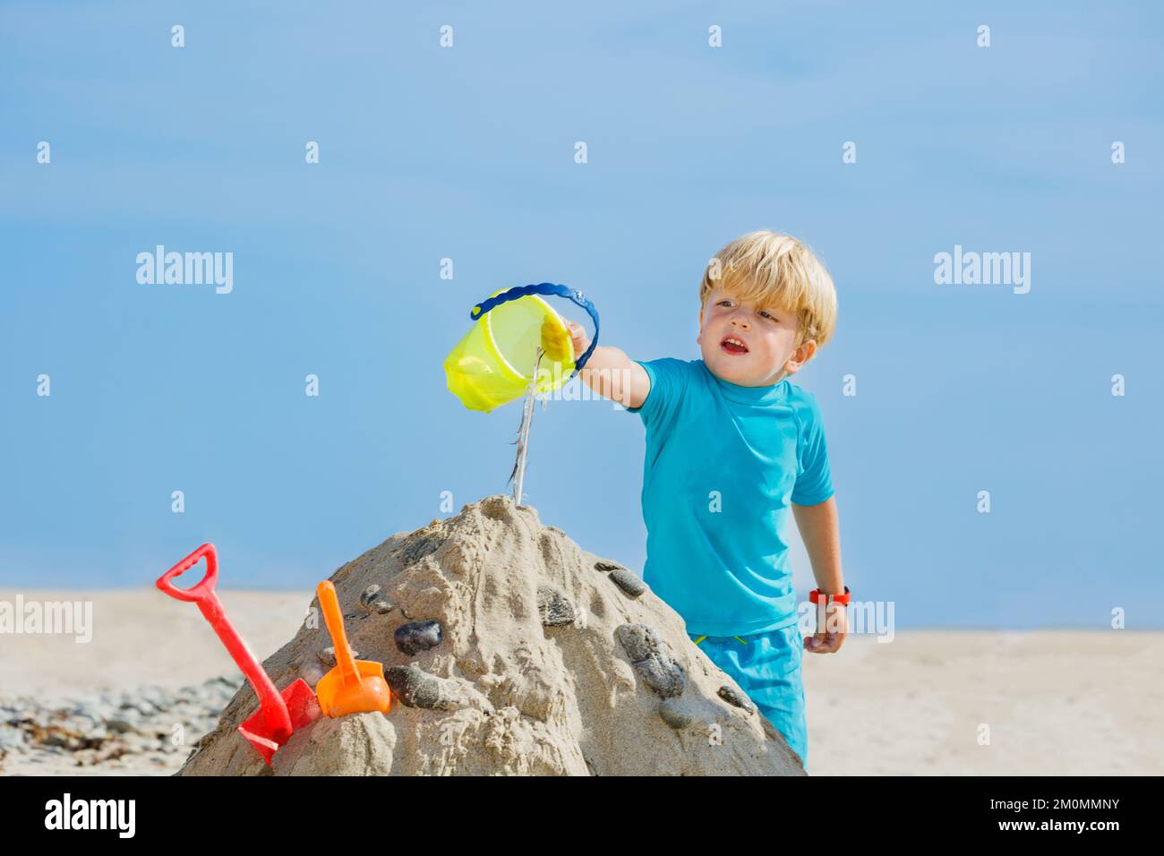 Handsome boy play with sand pouring water from plastic bucket Stock ...