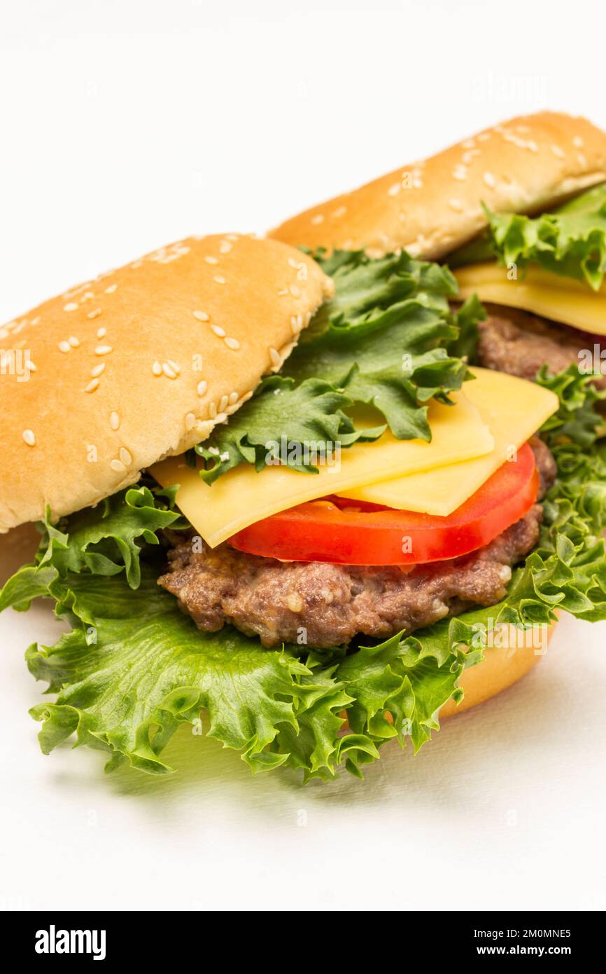 Burger bun on lettuce leaf with cheese and tomatoes. Top view. White ...