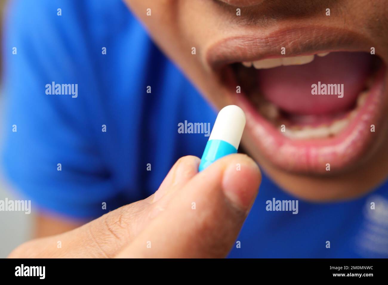 young men putting capsule in his mouth Stock Photo - Alamy