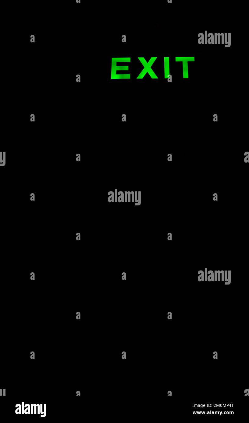 green neon exit panel with light on a dark black background in vertical ...