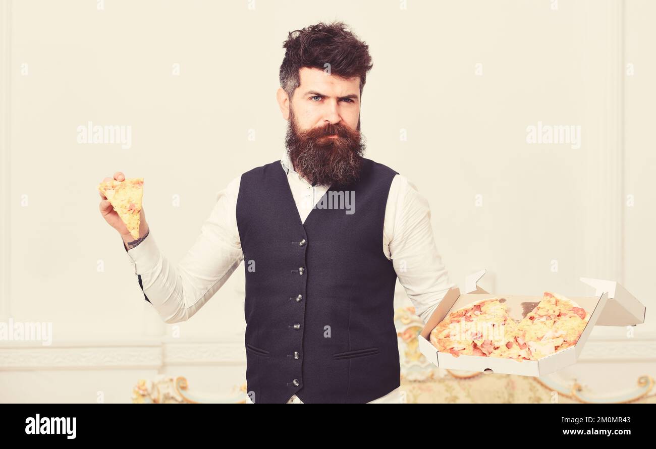Macho in classic clothes hungry, on strict face, holds slice of pizza ...