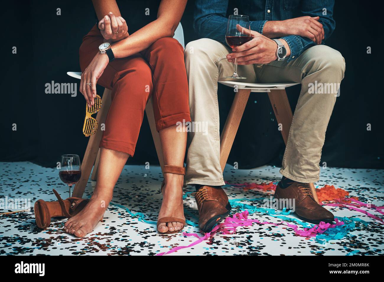 Feet, man and woman sitting at a party to celebrate new years eve and ...