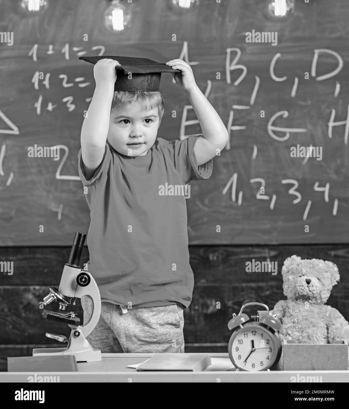 Kid boy in graduate cap ready to go to school, chalkboard on background ...