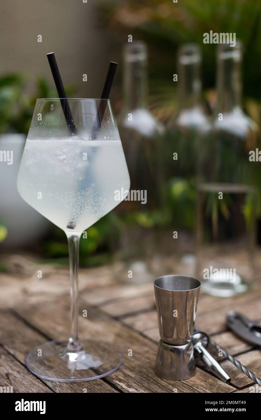 transparent cocktail with two straws in a glass with a stem on a wooden ...