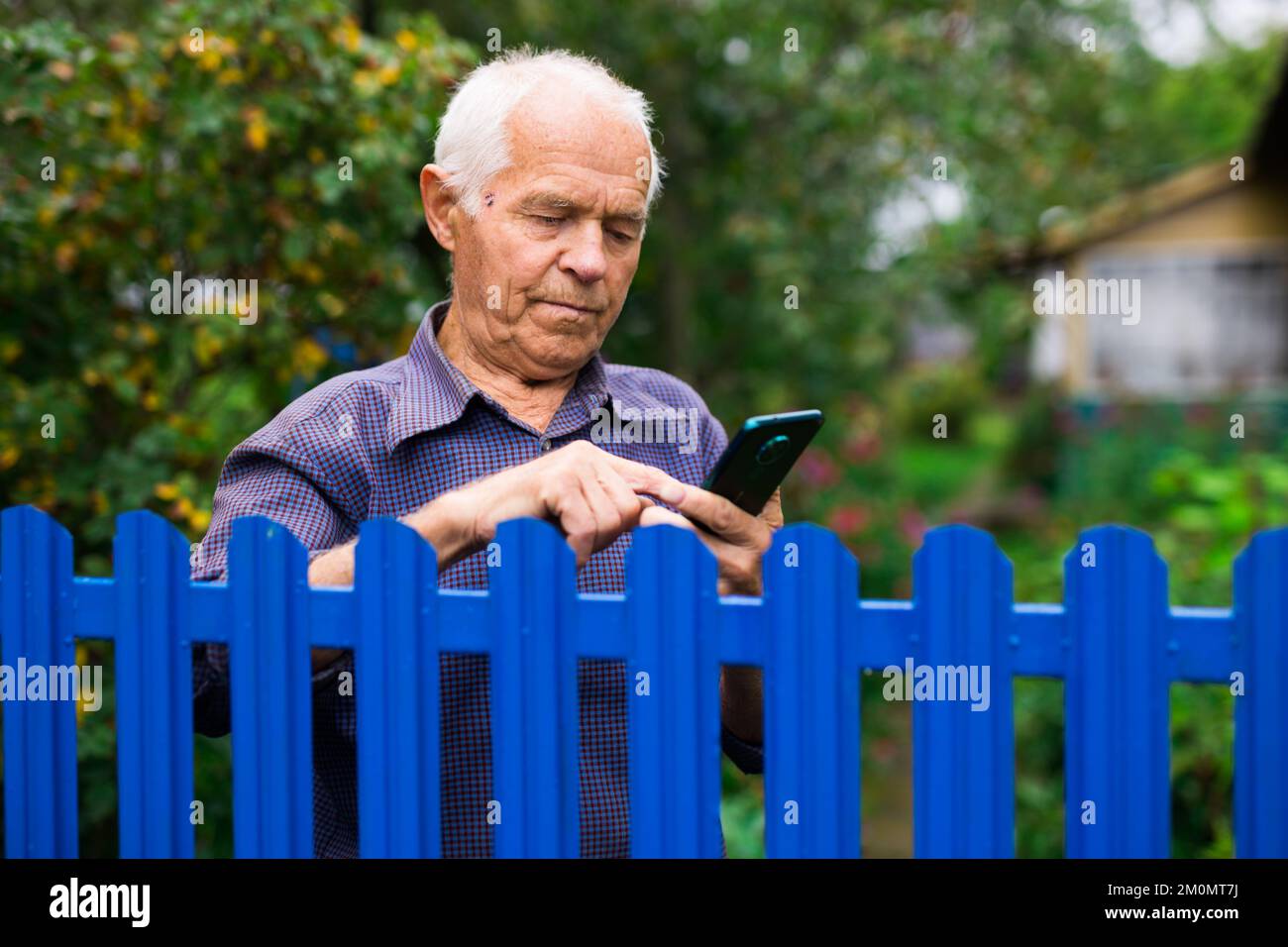 Elderly man writes message on smartphone. Concept of using digital ...