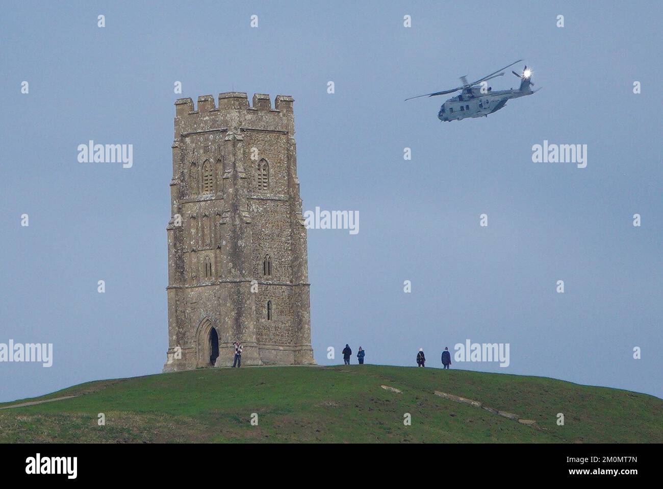 A Royal Navy Merlin helicopter flies above tourists exploring ...