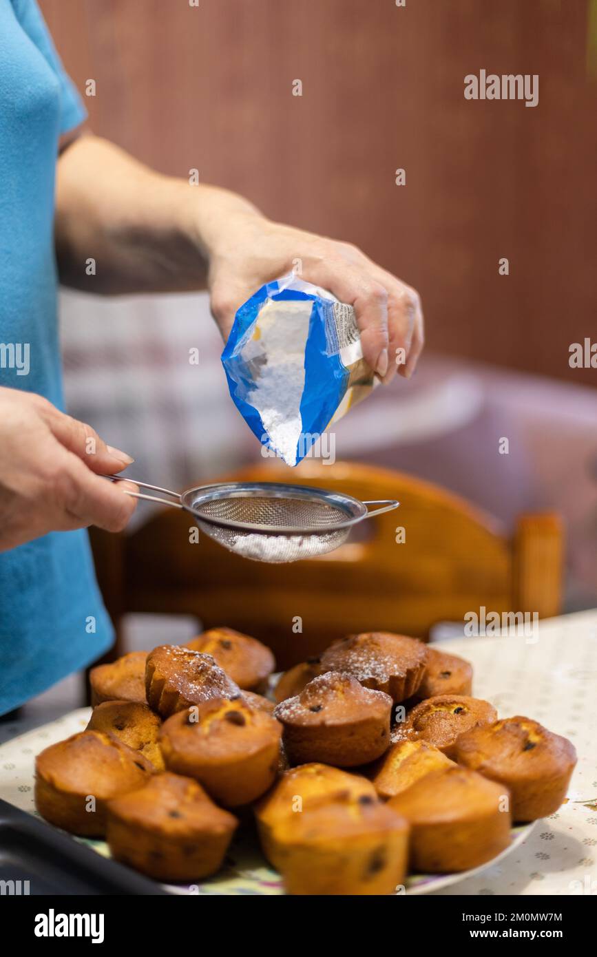 Woman topping cupcakes with powdered sugar. Baking at home. Selective ...