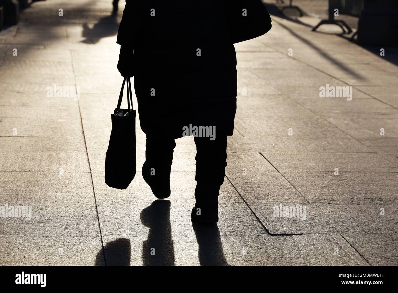 Silhouette of woman with handbag walking down the street, black shadow ...