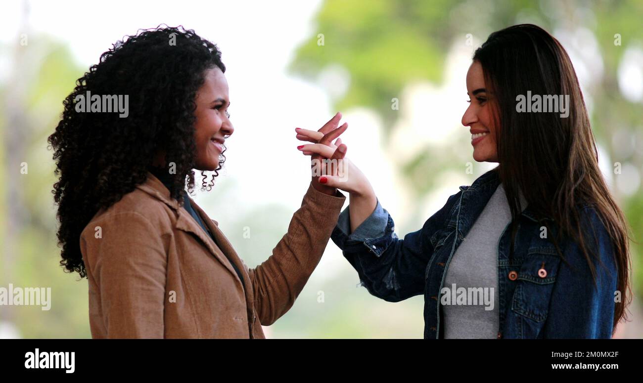 Two diverse young women joining hands in unity, black and white girls ...