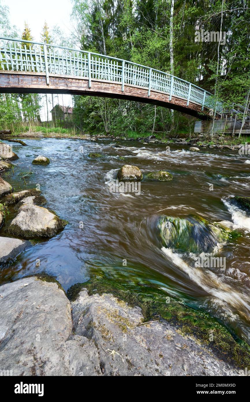 A vertical shot of a footbridge across a rocky river Stock Photo - Alamy