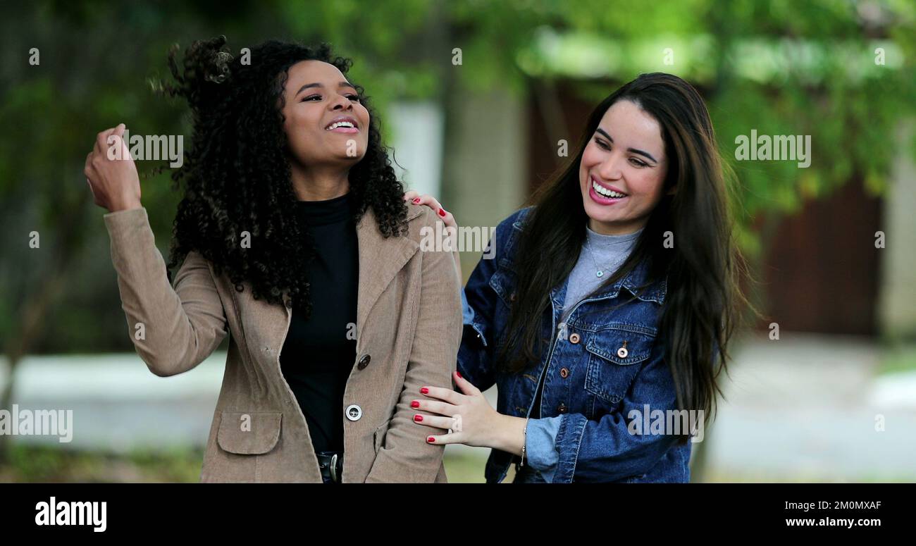 Two diverse friends laughing and smiling together outside. Two ...