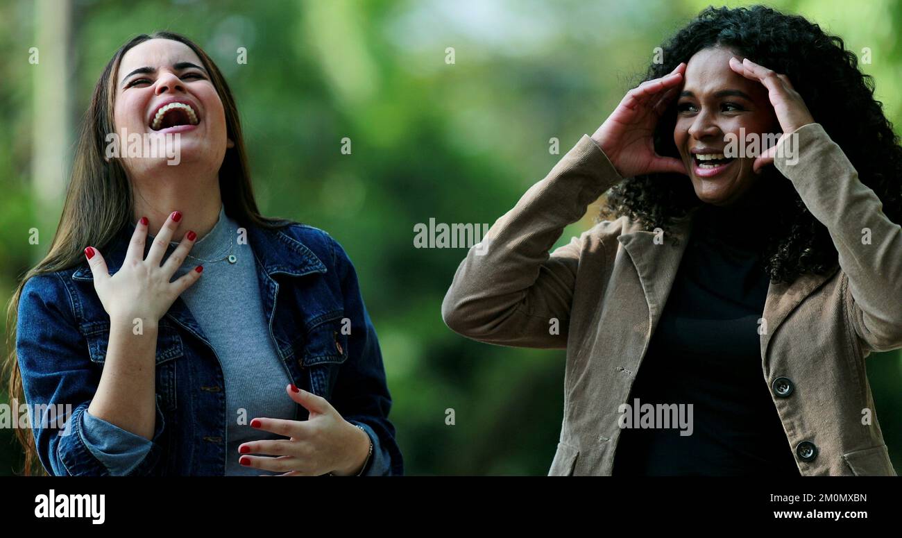Two candid women laughing and smiling together outside, real life laugh ...