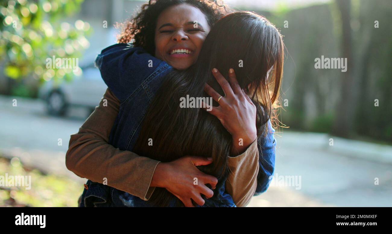 Two friends reunion meeting embrace and hug, outside in sunlight park ...