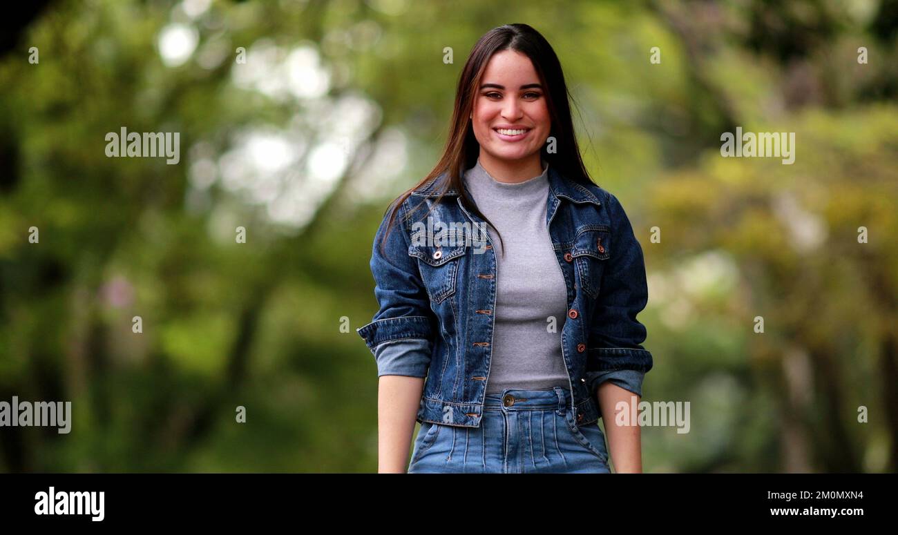 Pretty millennial girl standing outside smiling wearing jeans jacket ...