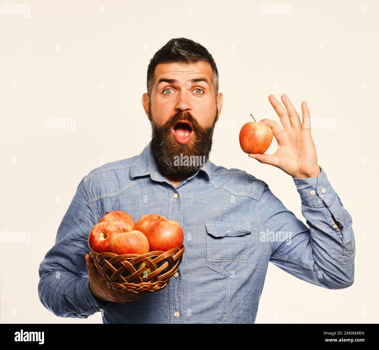 Farmer with surprised face holds red apple Stock Photo - Alamy