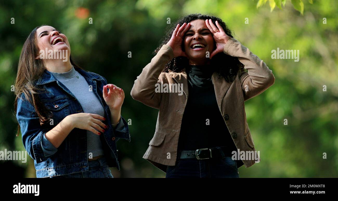 Two beautiful diverse girlfriends walking and laughing together while ...