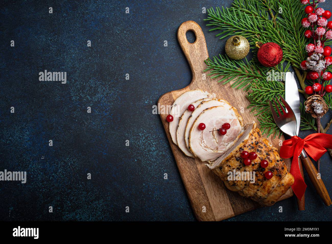 Christmas baked ham sliced with red berries and festive decorations ...