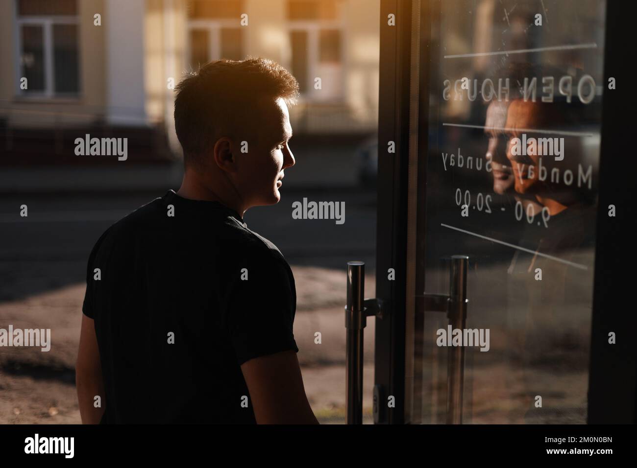 back view of confident young man opening the glass door while walking ...