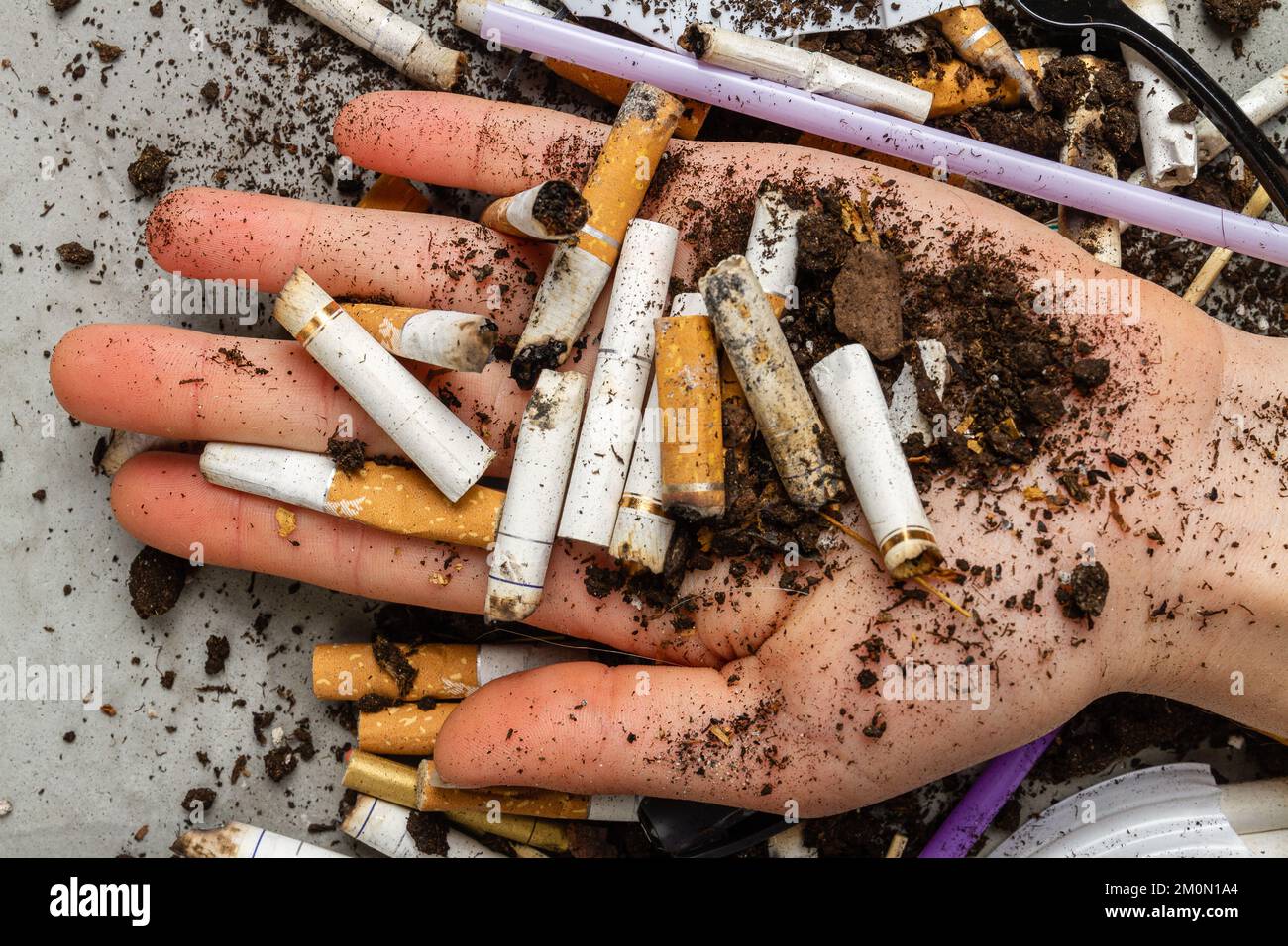 Close up hand holding pile of cigarettes with dirt. Concept of ...
