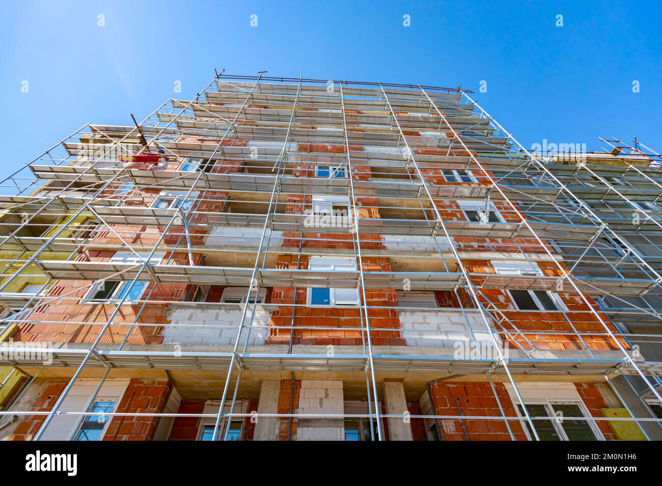 View from below on scaffold placed against unfinished edifice, new residential building under ...