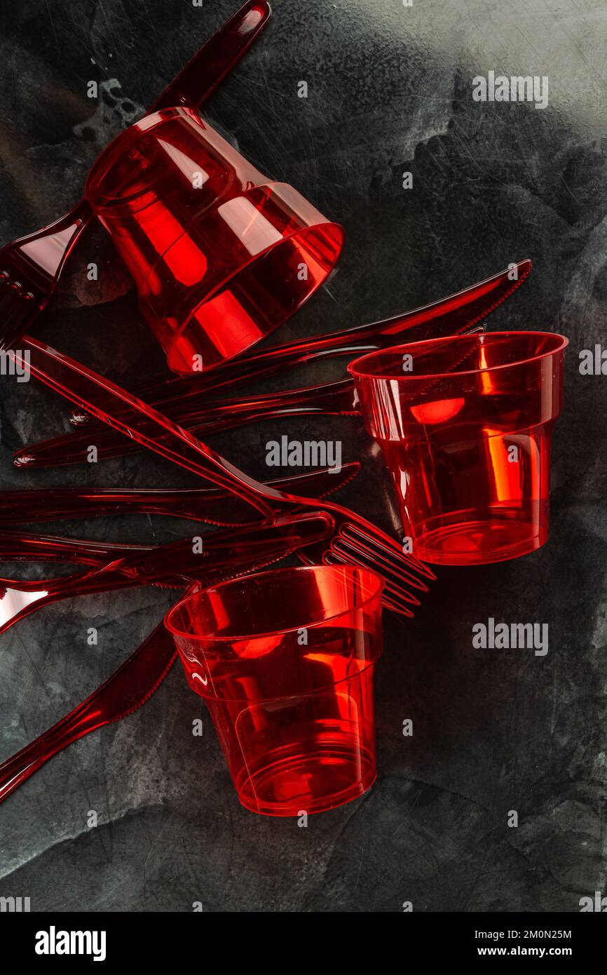 Red disposable plastic cups with forks and knives. Vertical shot top ...