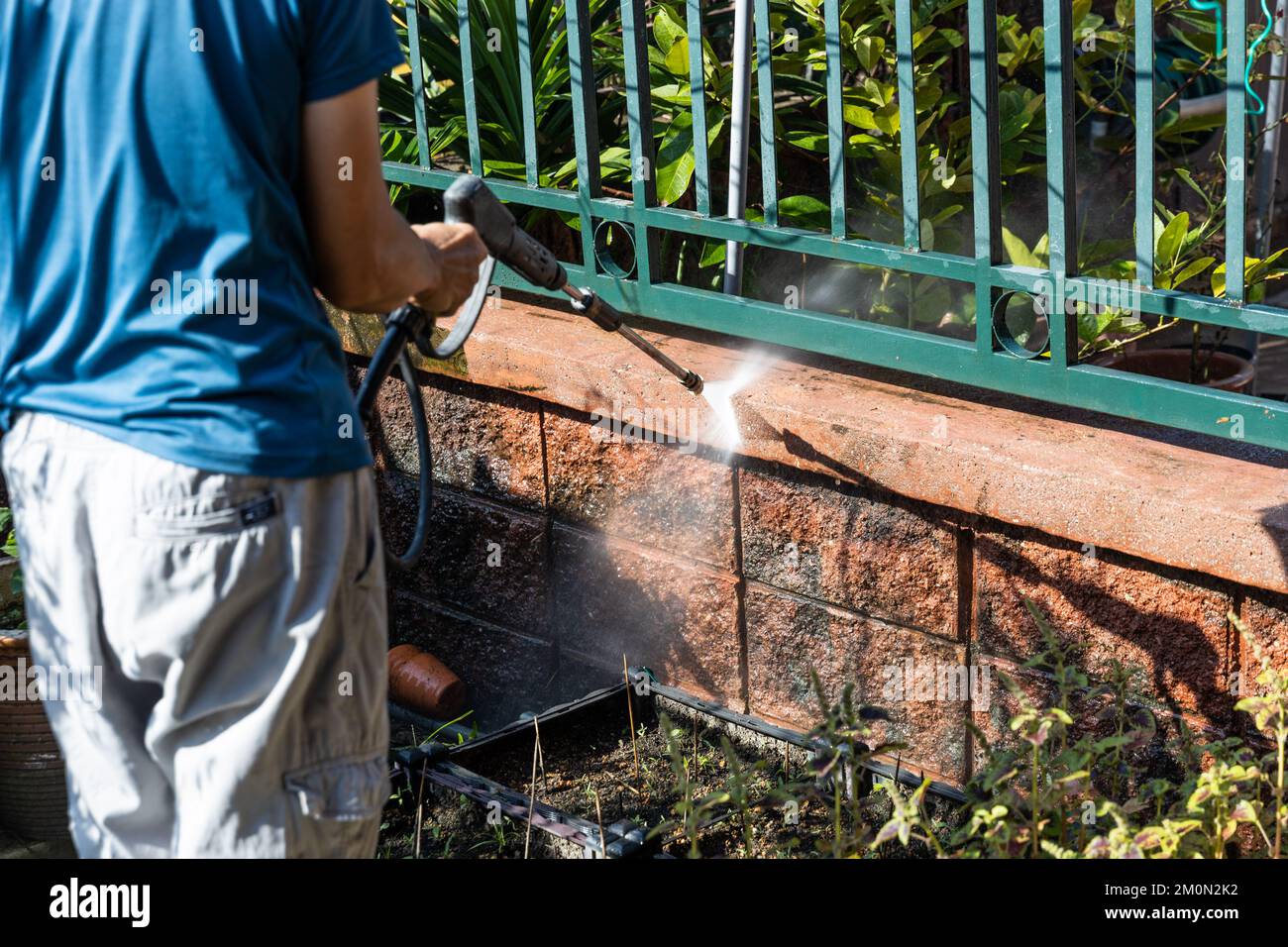 Worker using high pressure water jet spray gun to wash and clean away ...