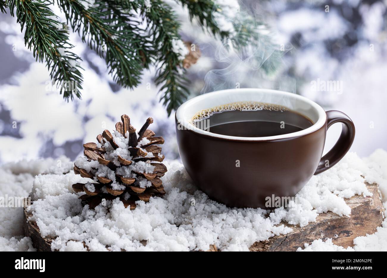 Steaming hot cup of coffee on a snow covered tree stump with a winter ...