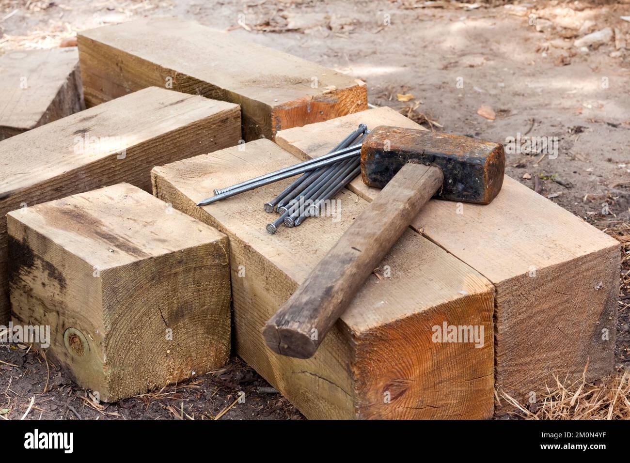 Vintage old rusty hammer and nails lying on wooden bars on the ground ...