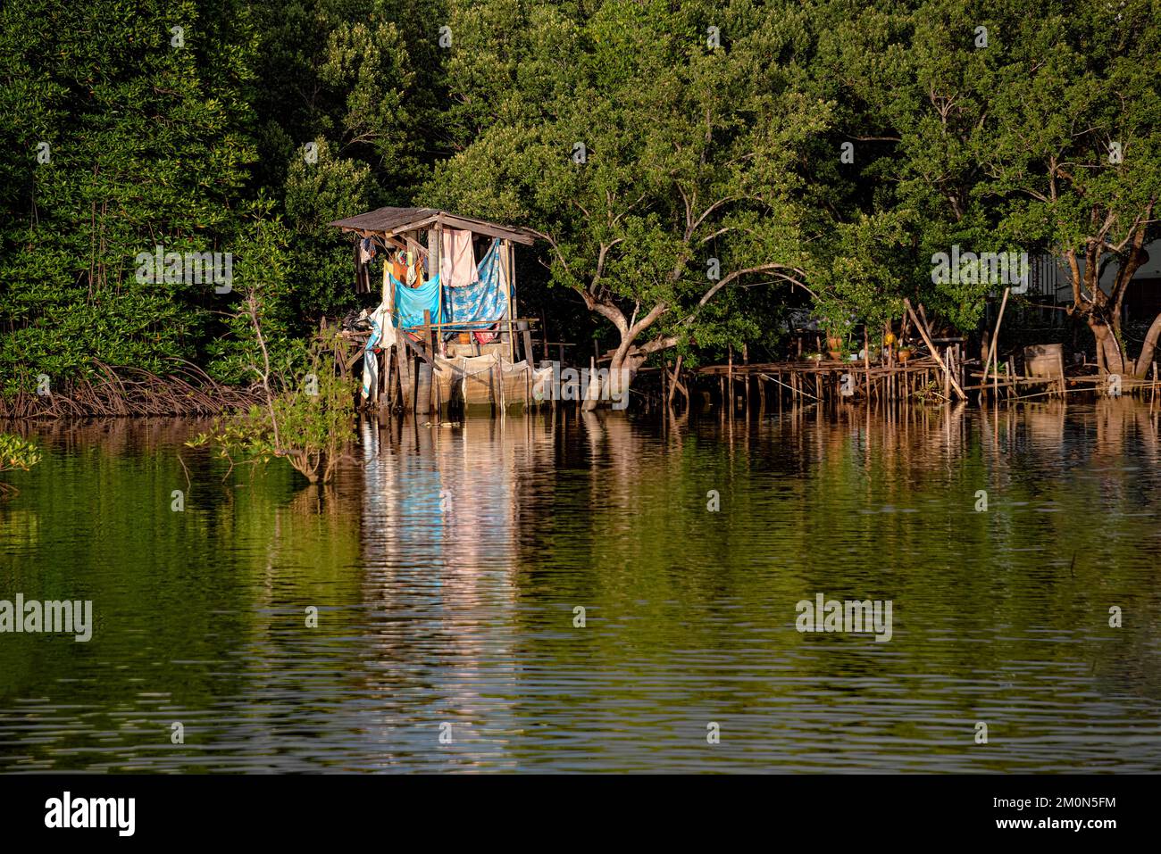 A poor little hut by the waterfront covered with clothes and sheets of ...