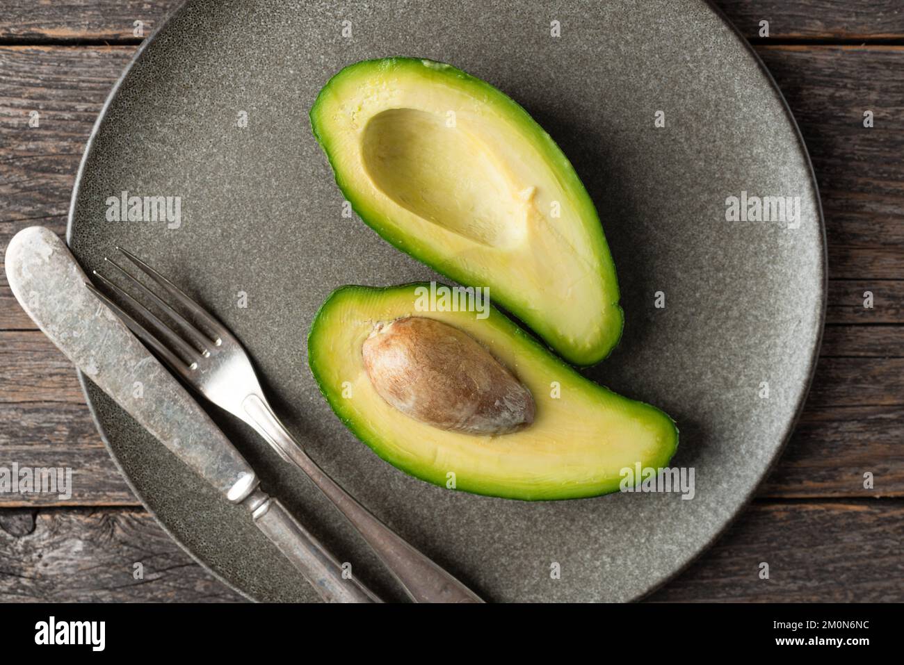 Avocado cut in halves on a plate, top view. Healthy food, clean eating ...