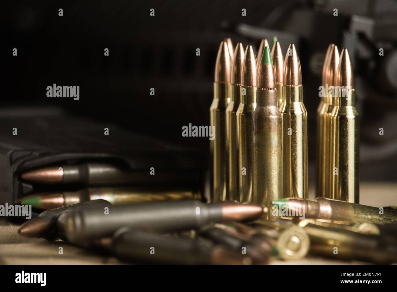 Various 223 rifle bullets standing or laying next to a full AR-15 ...