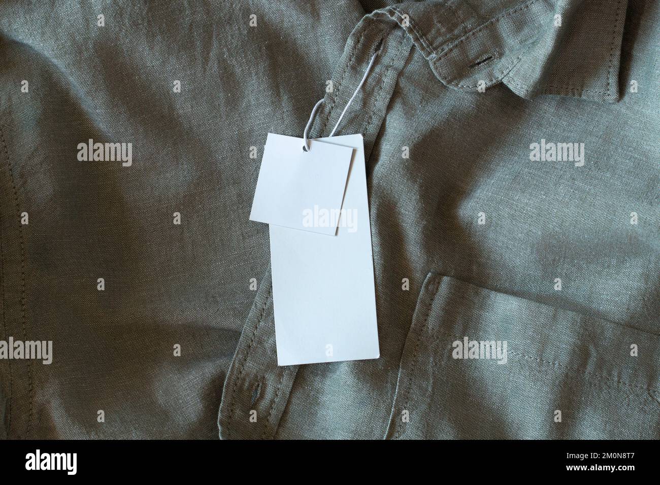 Blank price label tag paper card on gray natural linen shirt. Clothes ...