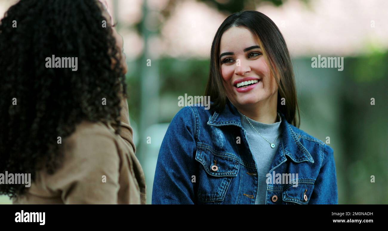 Two young women talking in conversation outside at park2 Stock Photo ...
