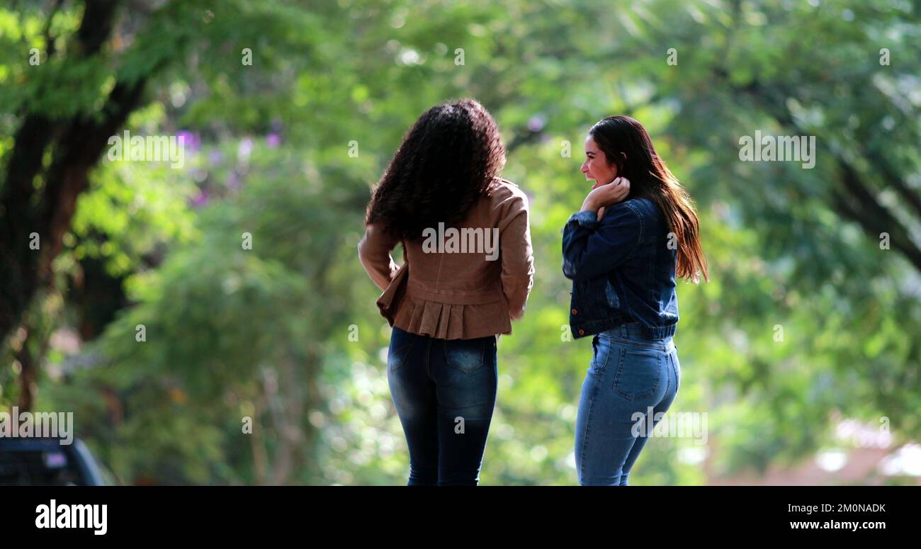 Two young women dancing in celebration outside, back view of two girls ...