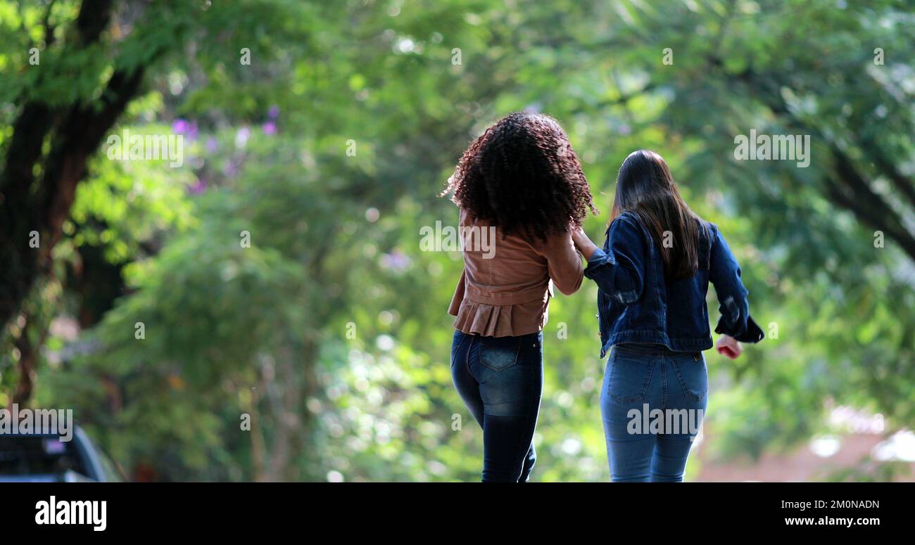 Two young women dancing in celebration outside, back view of two girls ...
