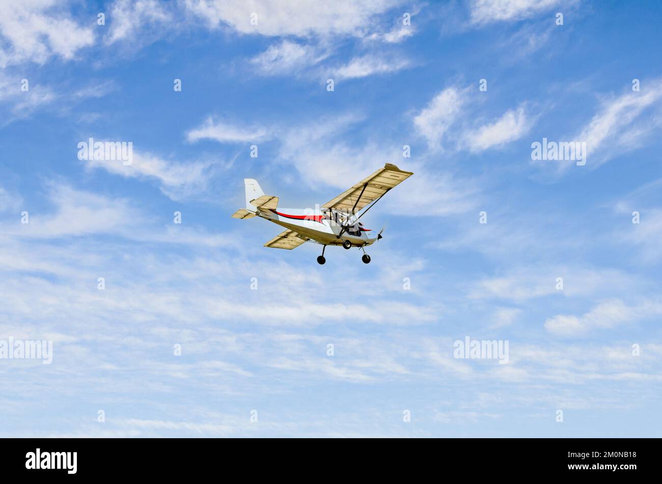 Single engine ultralight plane flying in the blue sky with white clouds ...
