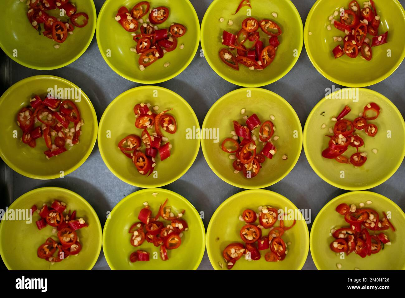 A top view of small plates of cute red chilies on the grey background ...