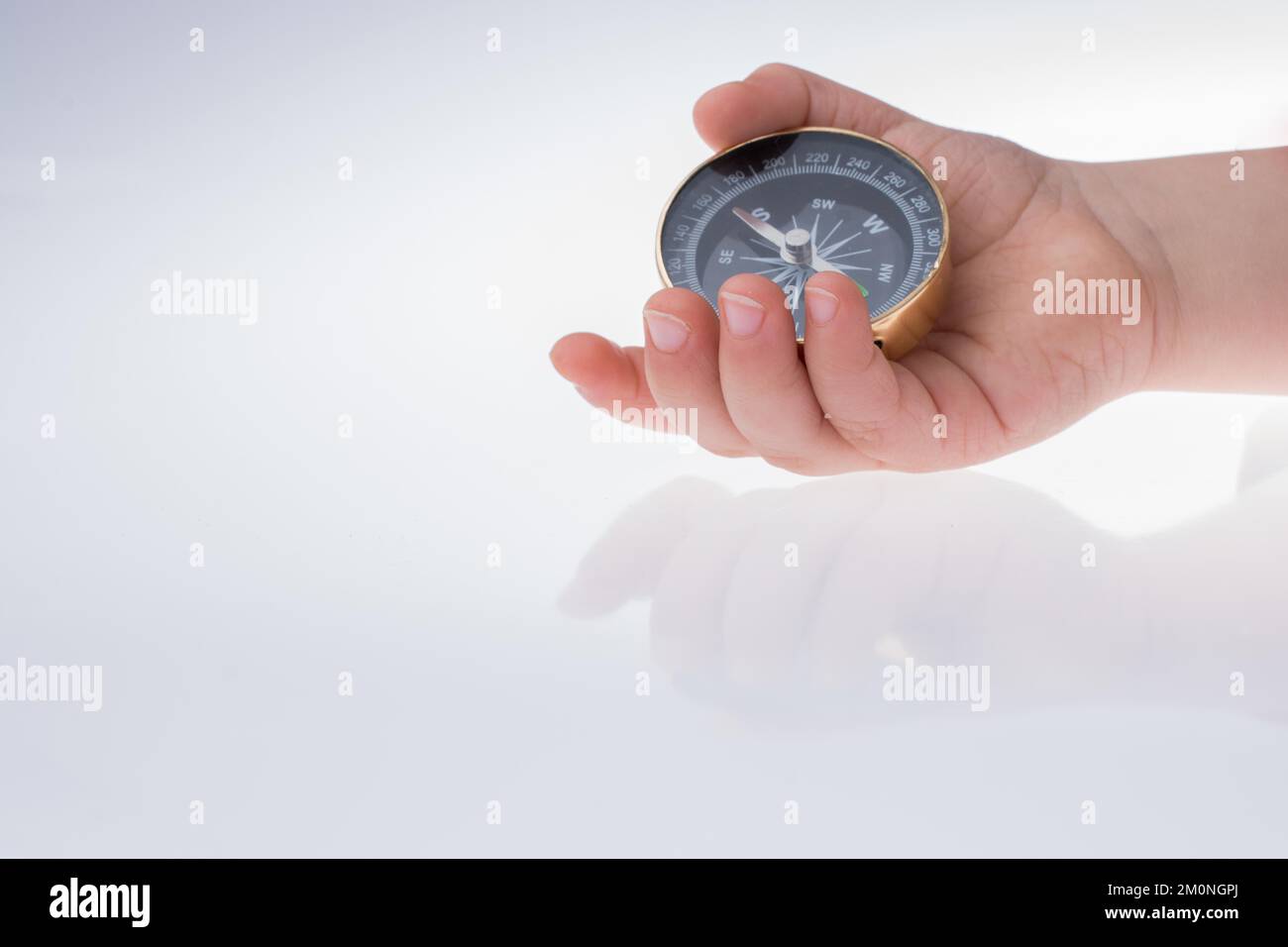 Child hand holding a compass on a white background Stock Photo - Alamy