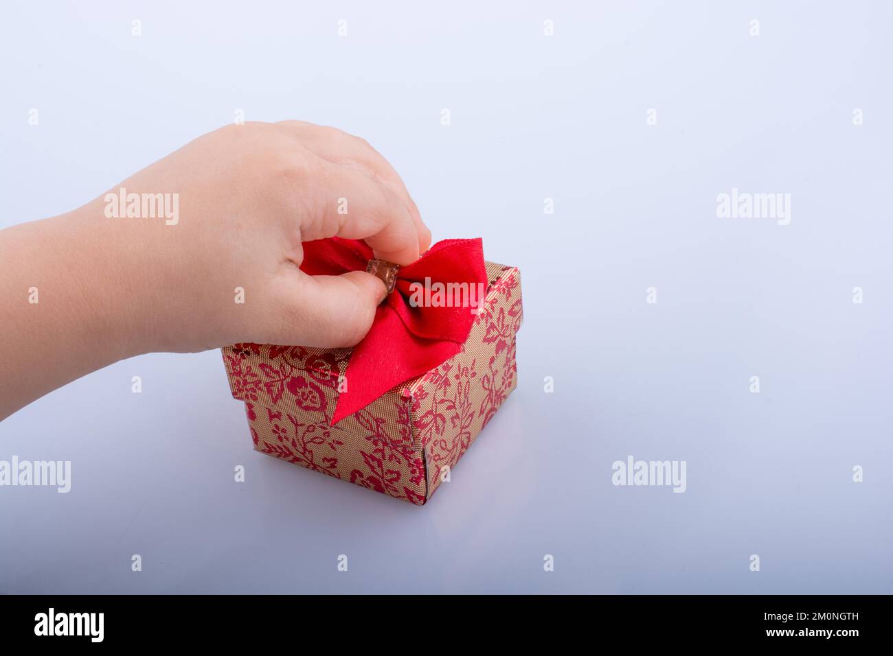 Hand holding a gift box with a red ribbon Stock Photo - Alamy
