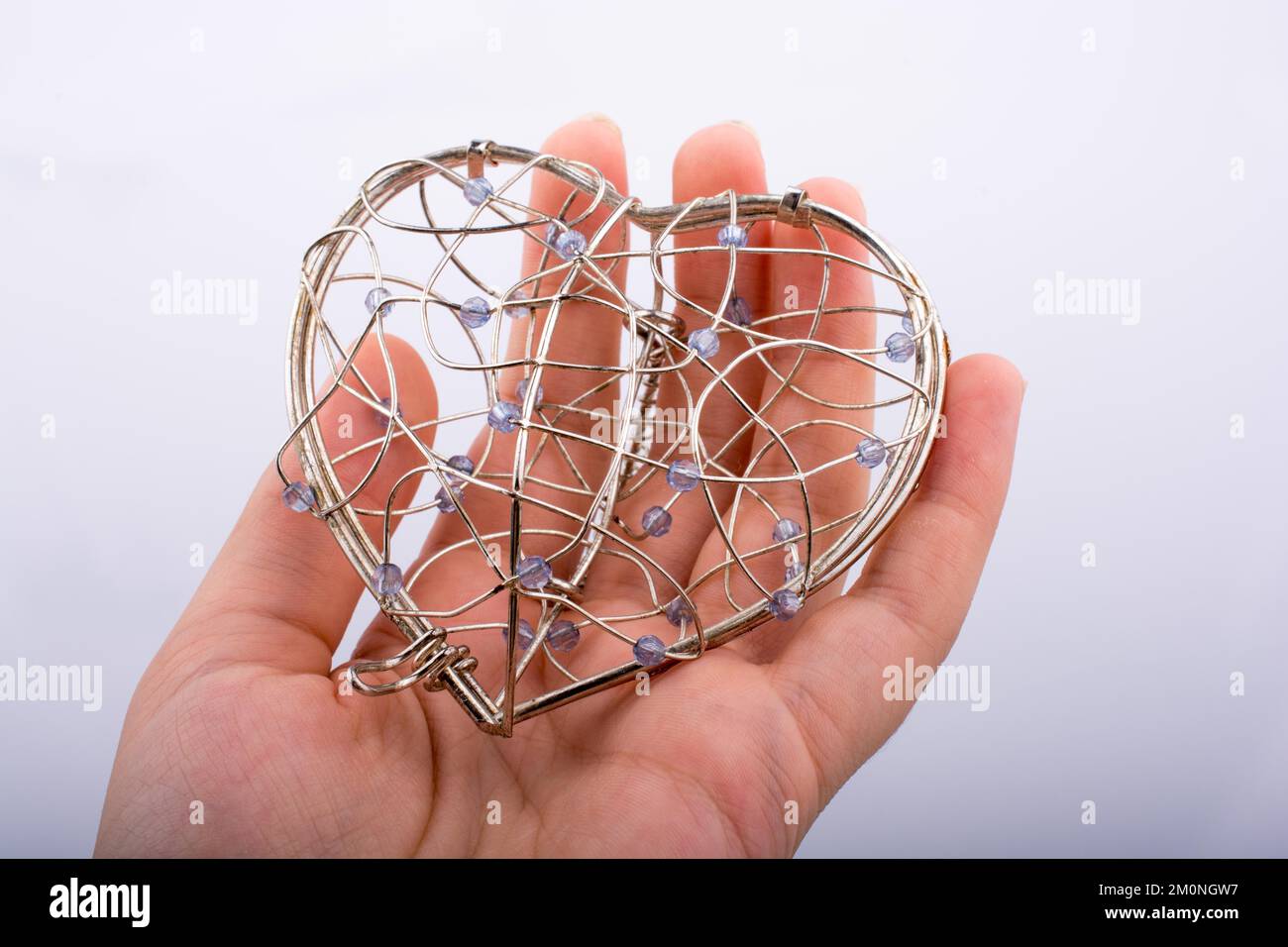 Heart shaped silver color metal wire cage in hand Stock Photo - Alamy